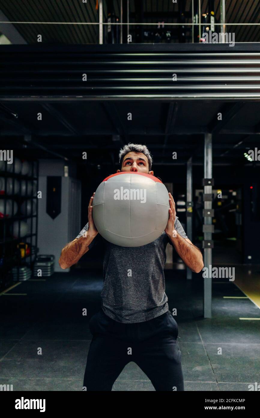 Strong determined athletic male holding medicine ball during workout in ...
