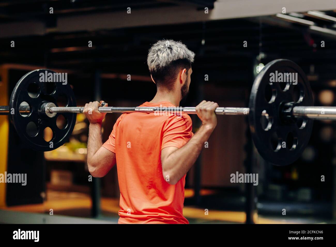 From behind view of male athlete lifting heavy barbell during intense ...