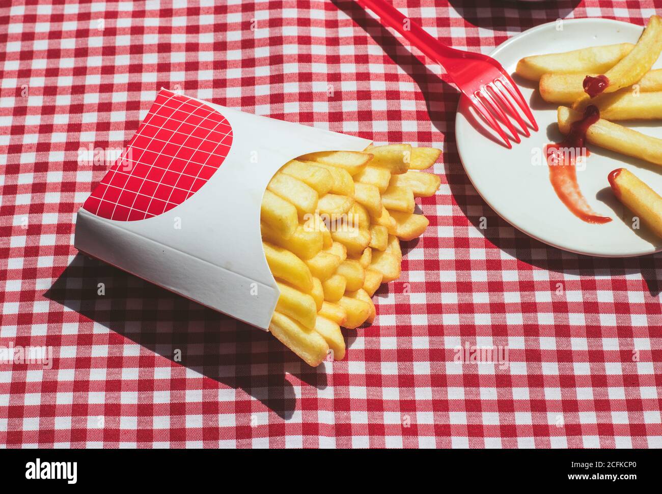 From above french fries packet near plate with potatoes soaked in ...