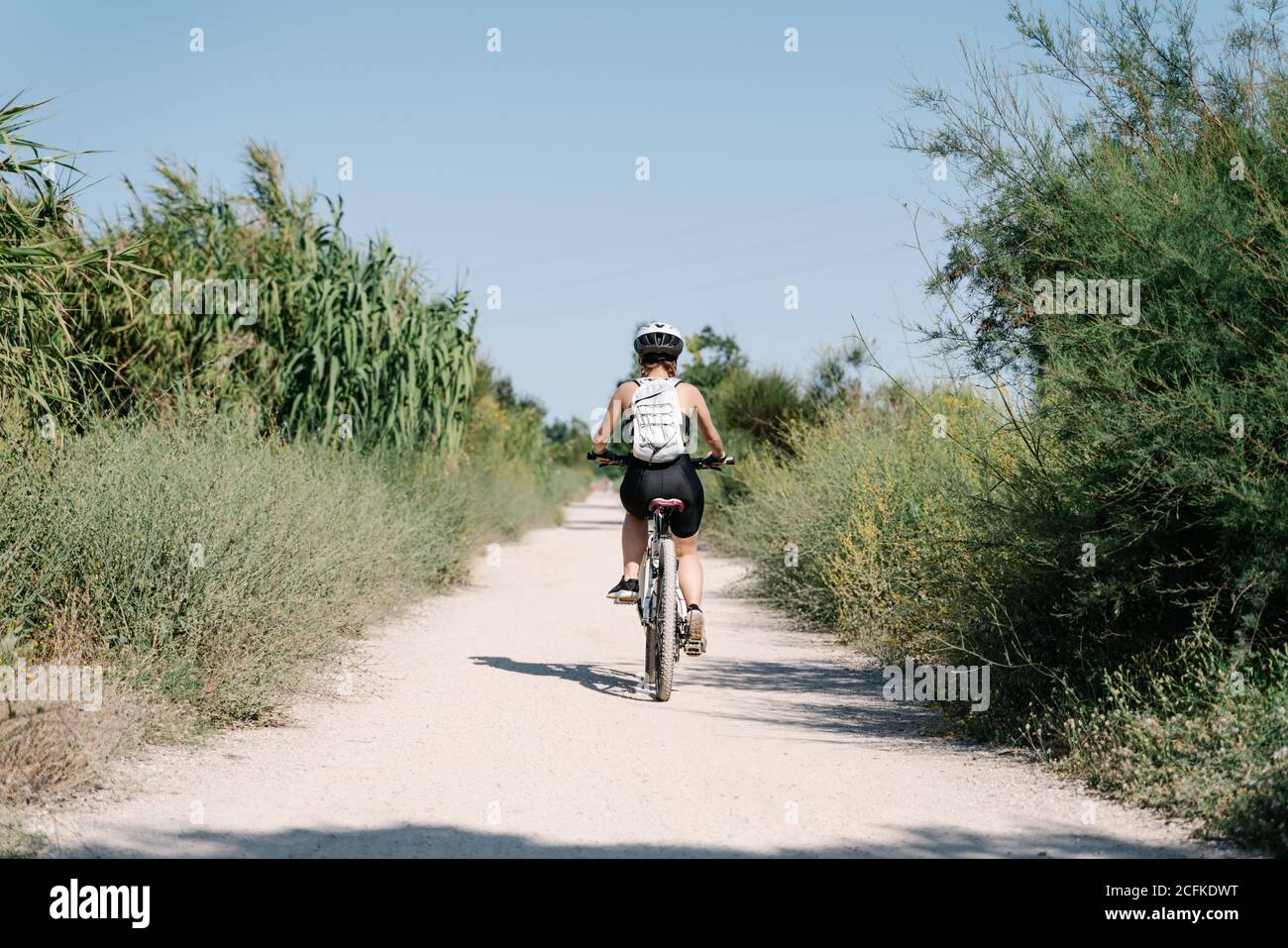 Full body of positive young female cyclist in sportswear and helmet ...