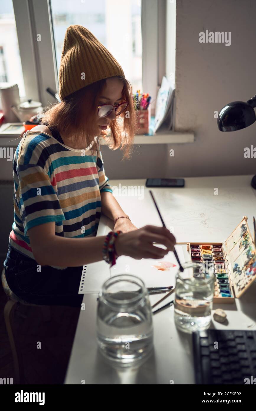 High angle side view of concentrated female artist standing at table in ...