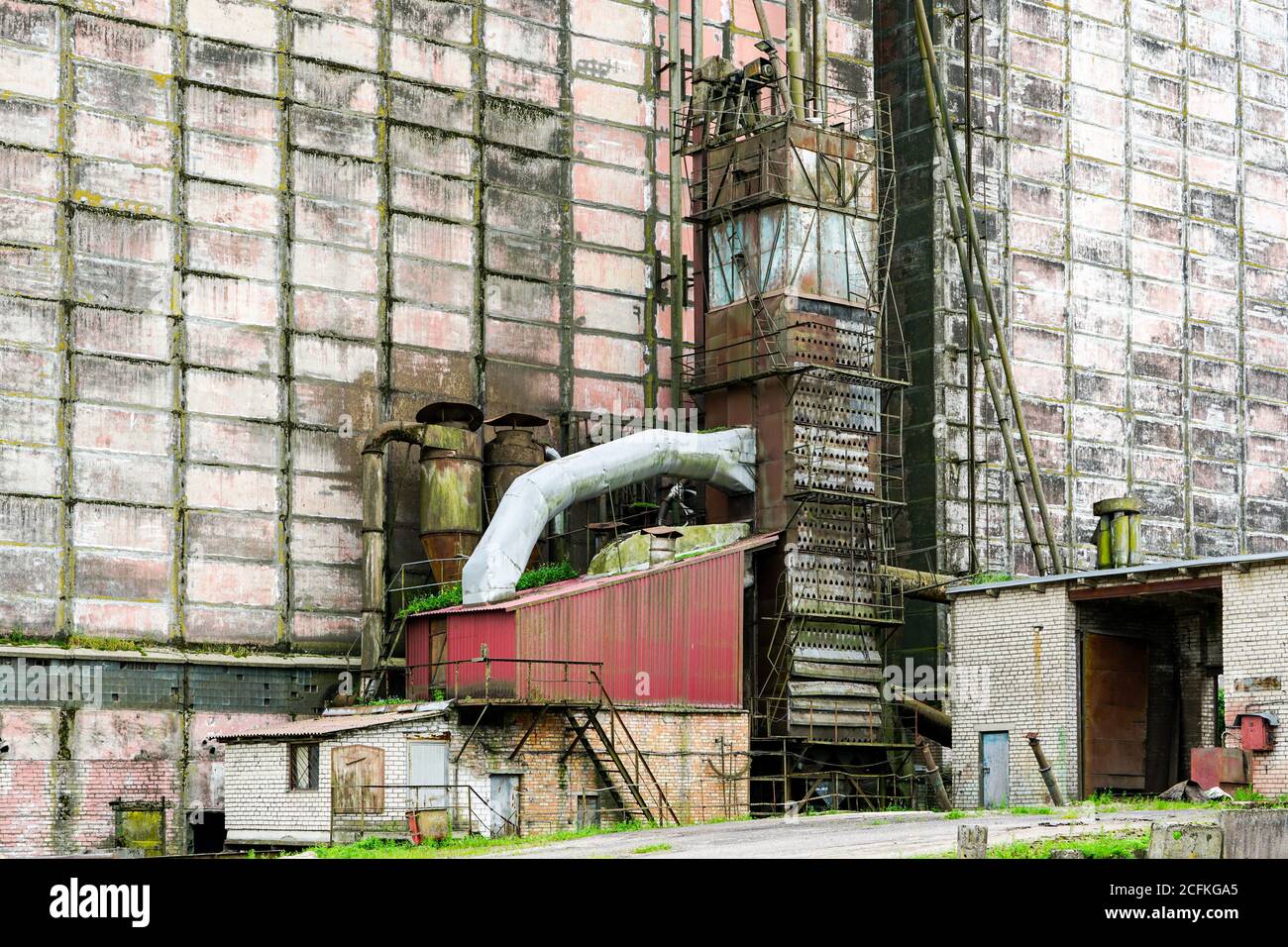 old factory building wall with auxiliary buildings and various pipes ...