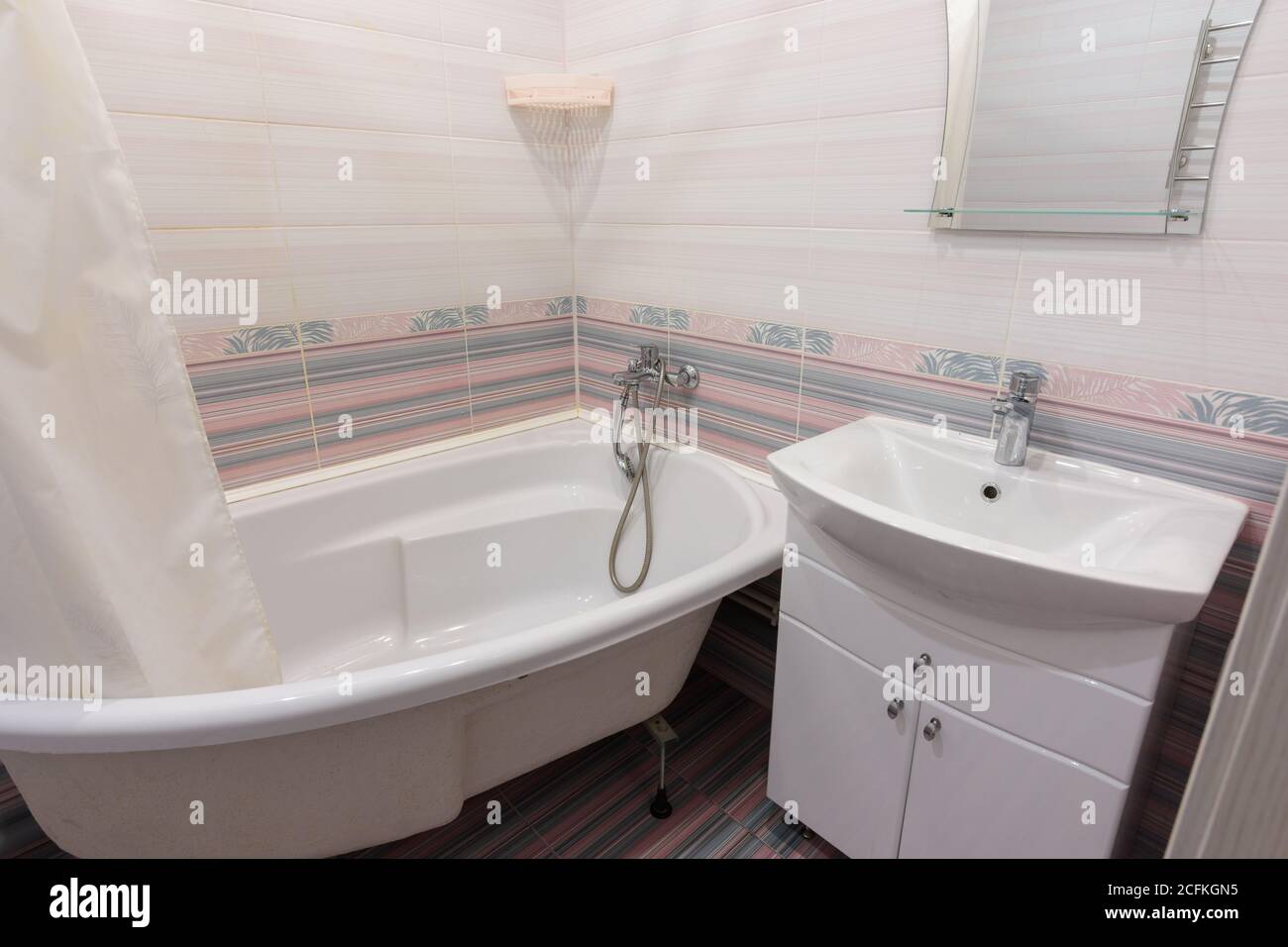 Interior of a cozy ordinary bathroom with a washbasin, a bathtub and a ...