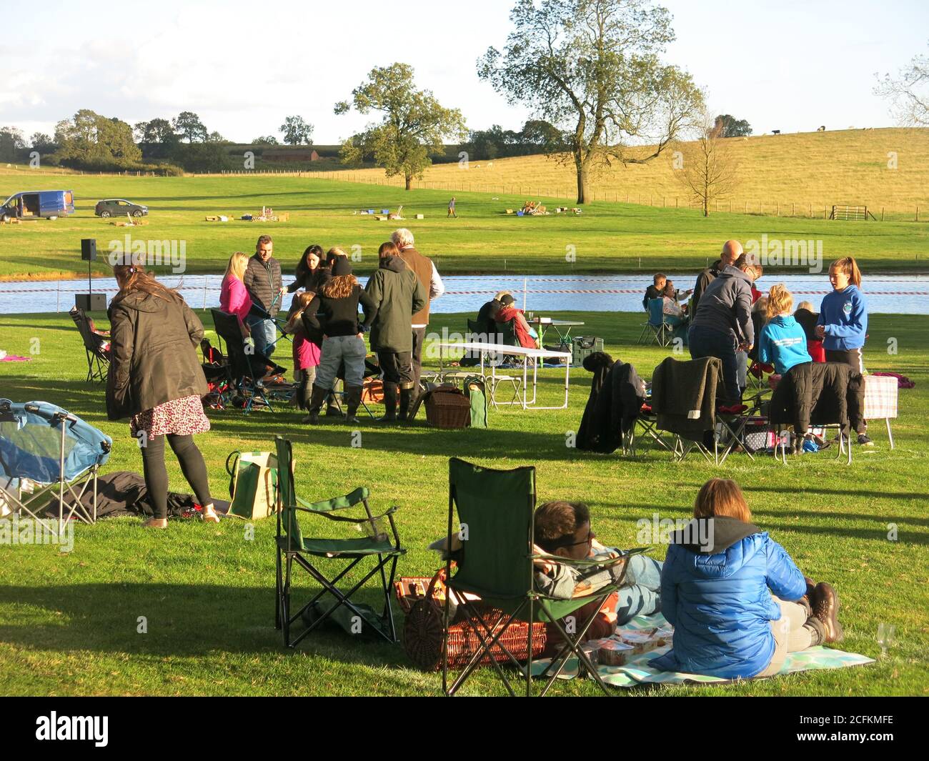 Picnickers in a field early evening in autumn for a charity film-show ...