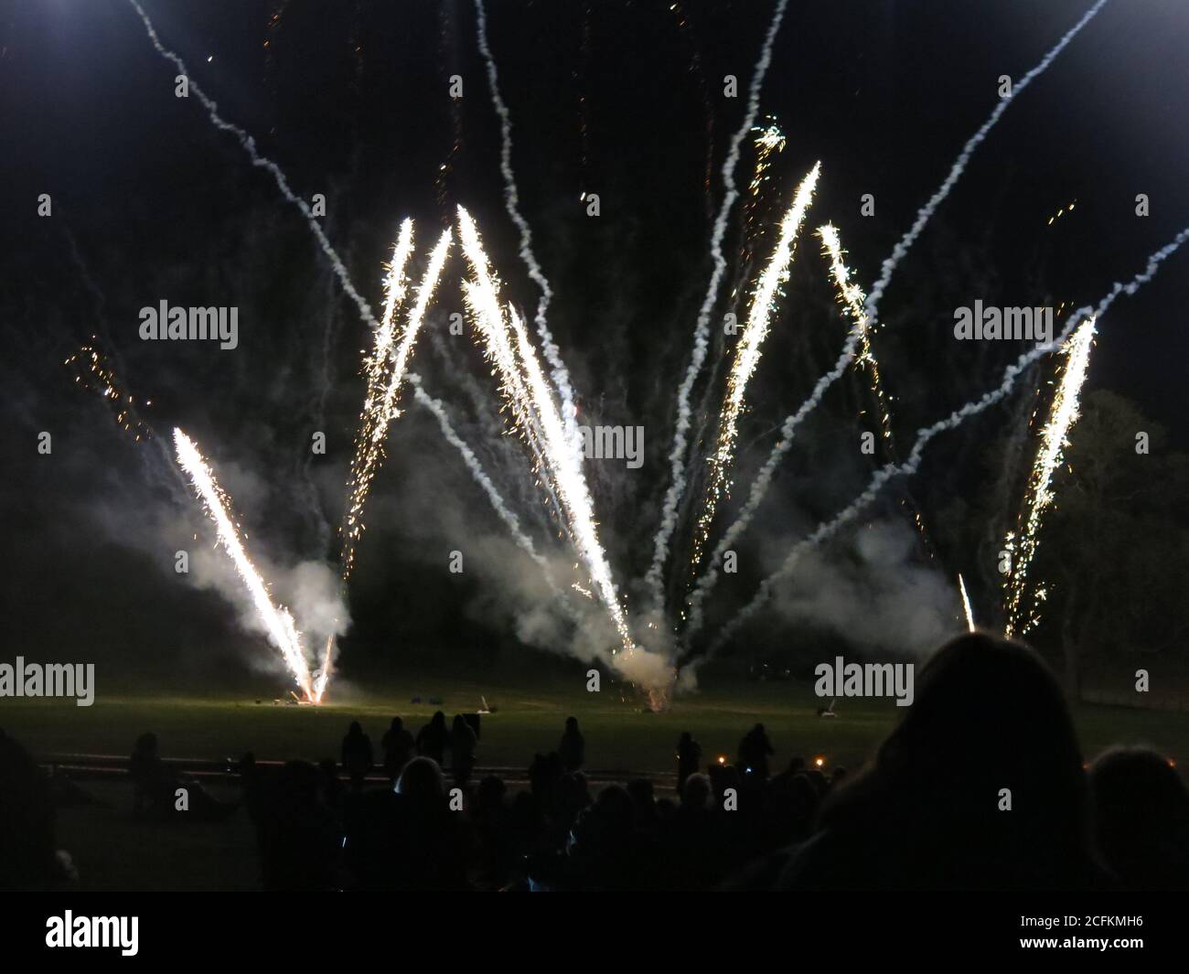 At a firework display with vertical white lights and smoke trails from ...