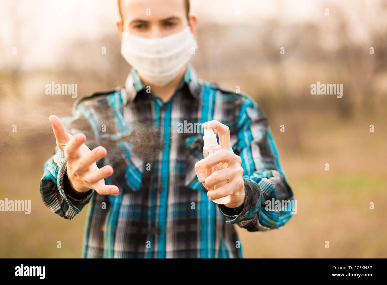 Man wearing disposable medical face mask makes disinfection of hands ...