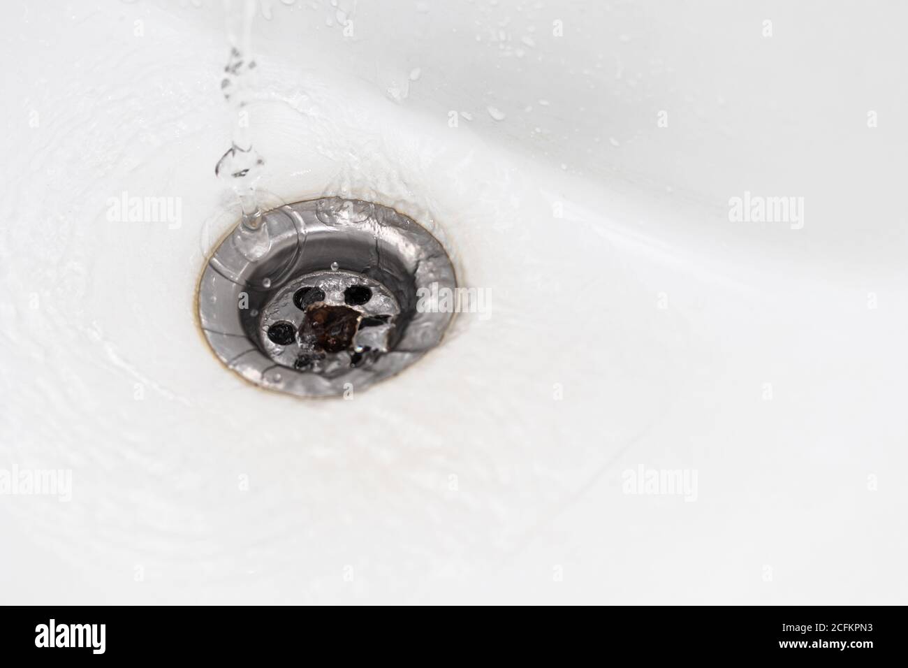 Close up a stream of clean water flows into the sink sewer hole. A jet ...