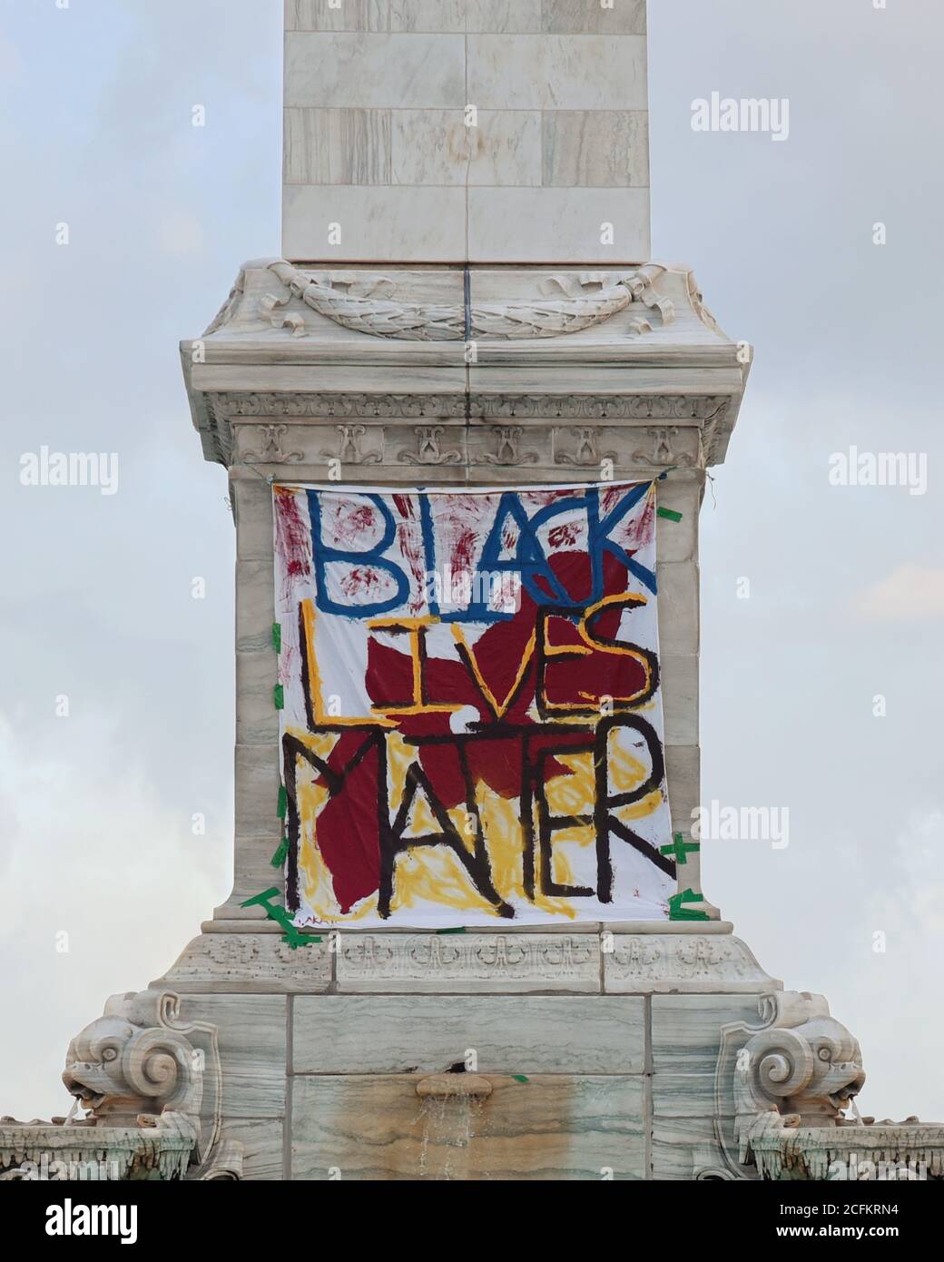 A sign is hanging on a stone wall outside that reads Black Lives Matter ...