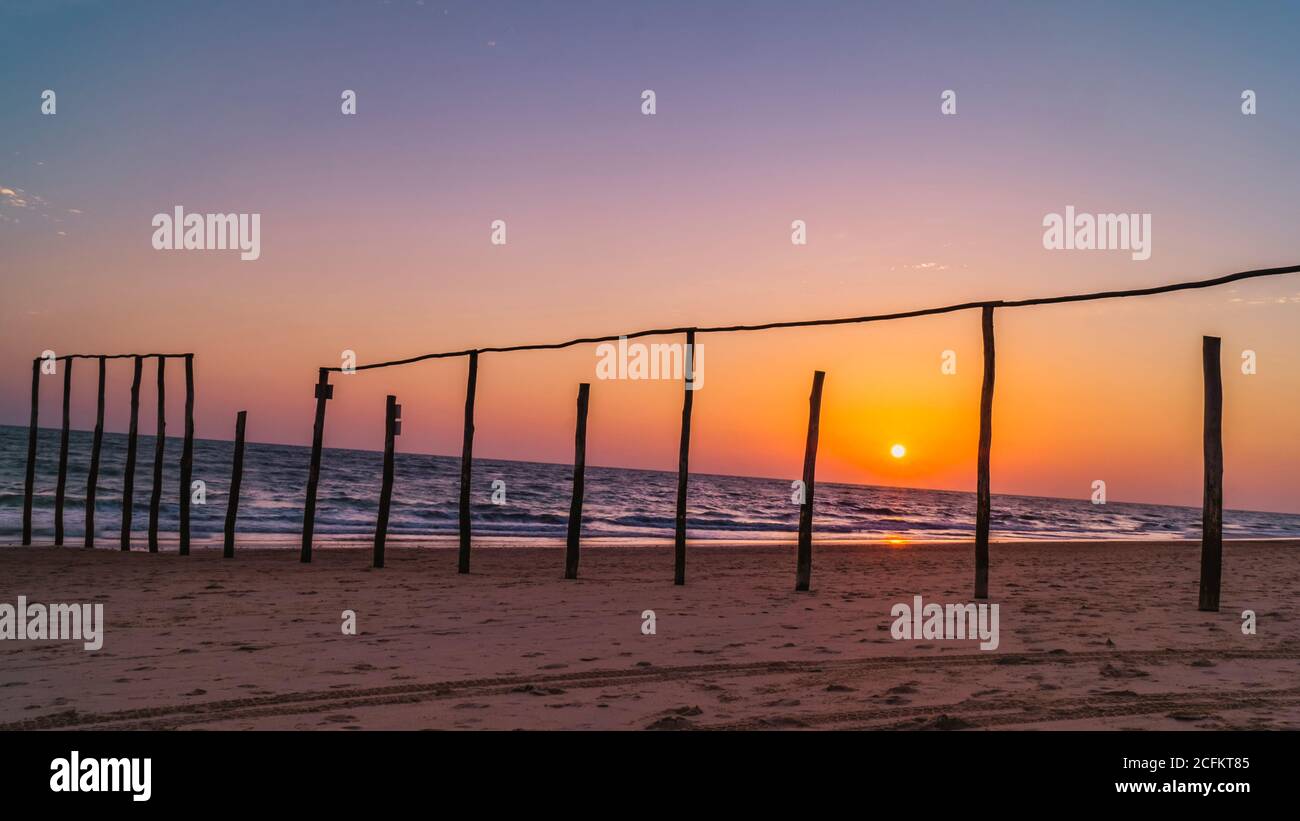 wooden poles on the beach at sunset glow Stock Photo - Alamy