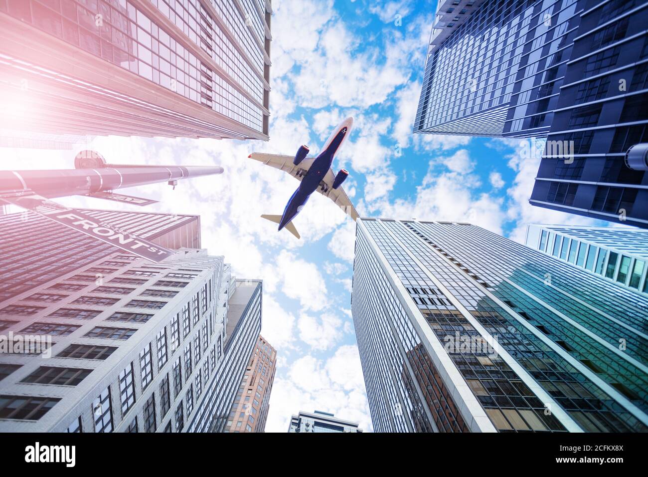 Plane over sky between skyscraper buildings in New York Front street ...