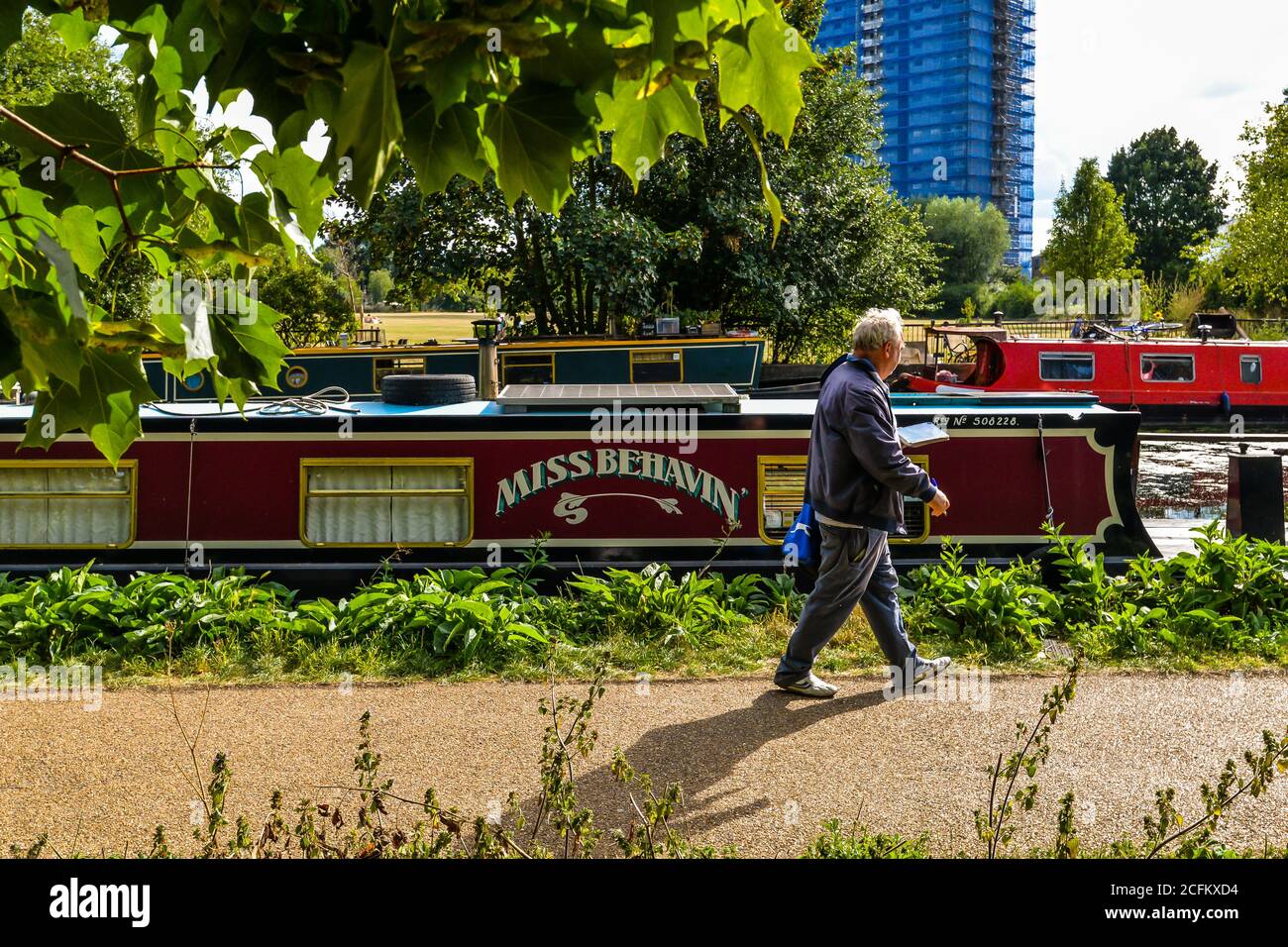 London/UK - 8/9/20 - A man walking past a canal boat with Miss Behavin ...