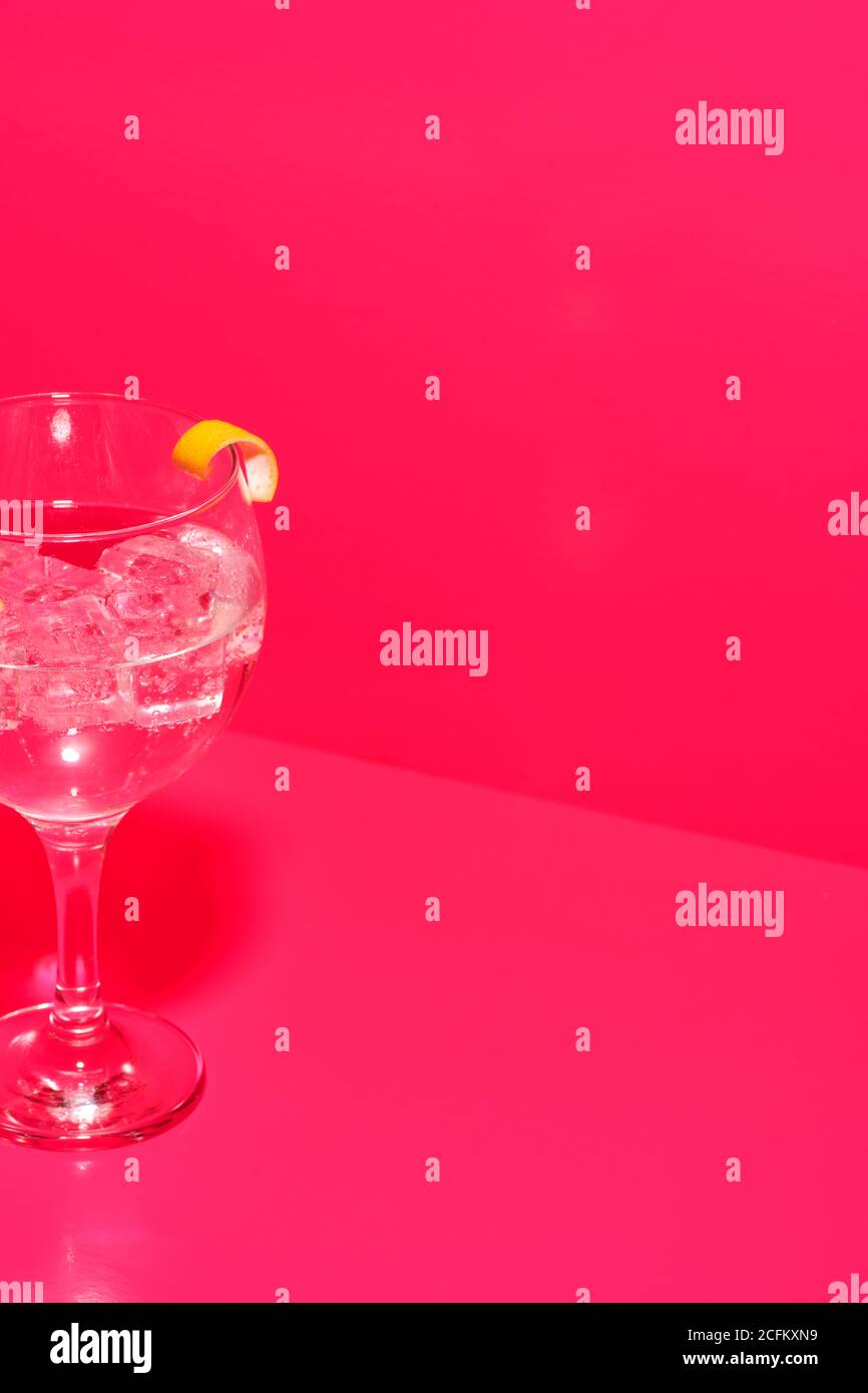 Transparent glass of tasty gin tonic cocktail with ice with lemon twist ...