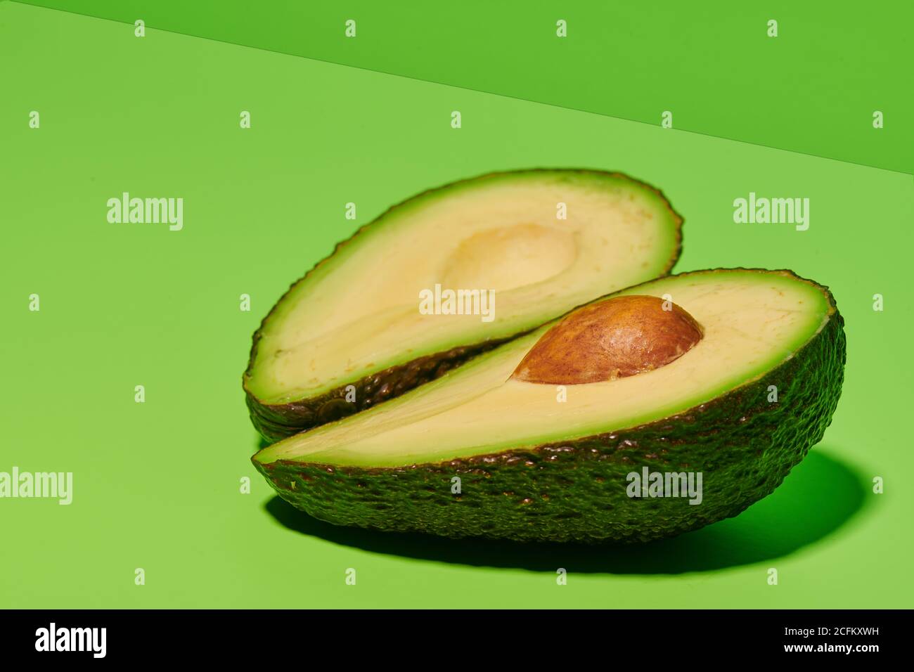 Fresh green natural avocado cut in half with seed placed on bright ...