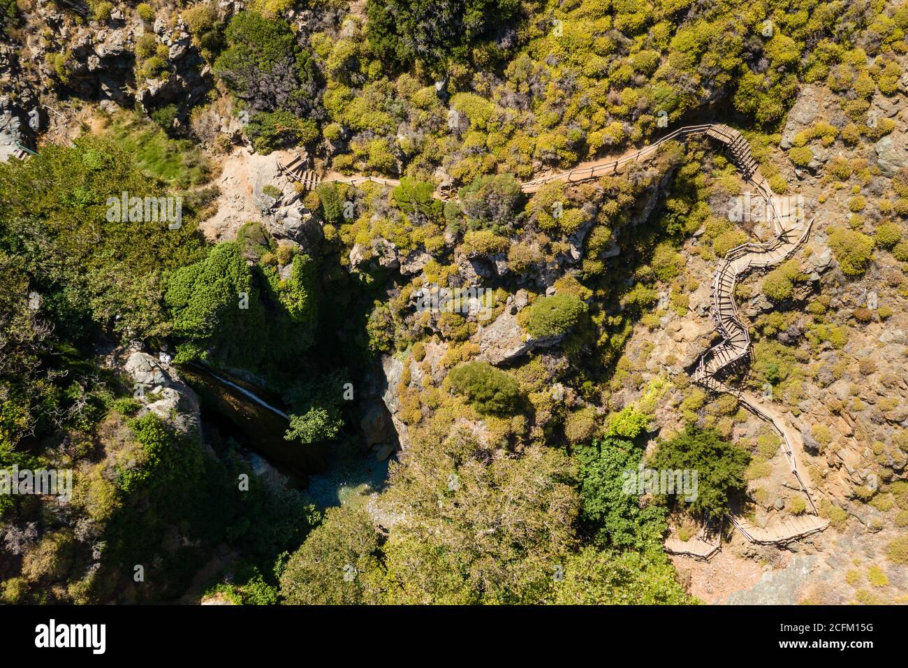 Aerial view of a waterfall in a narrow gorge next to winding wooden ...