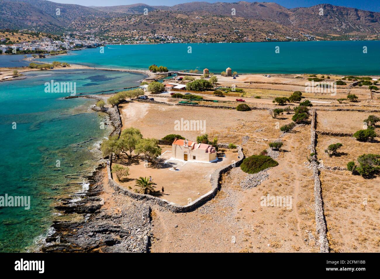 Aerial view of a small church next to a blue ocean on a hot Greek ...