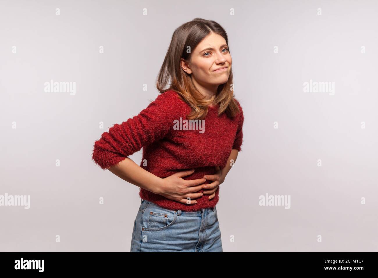 Girl in shaggy sweater touching belly, grimacing from stomach ache ...