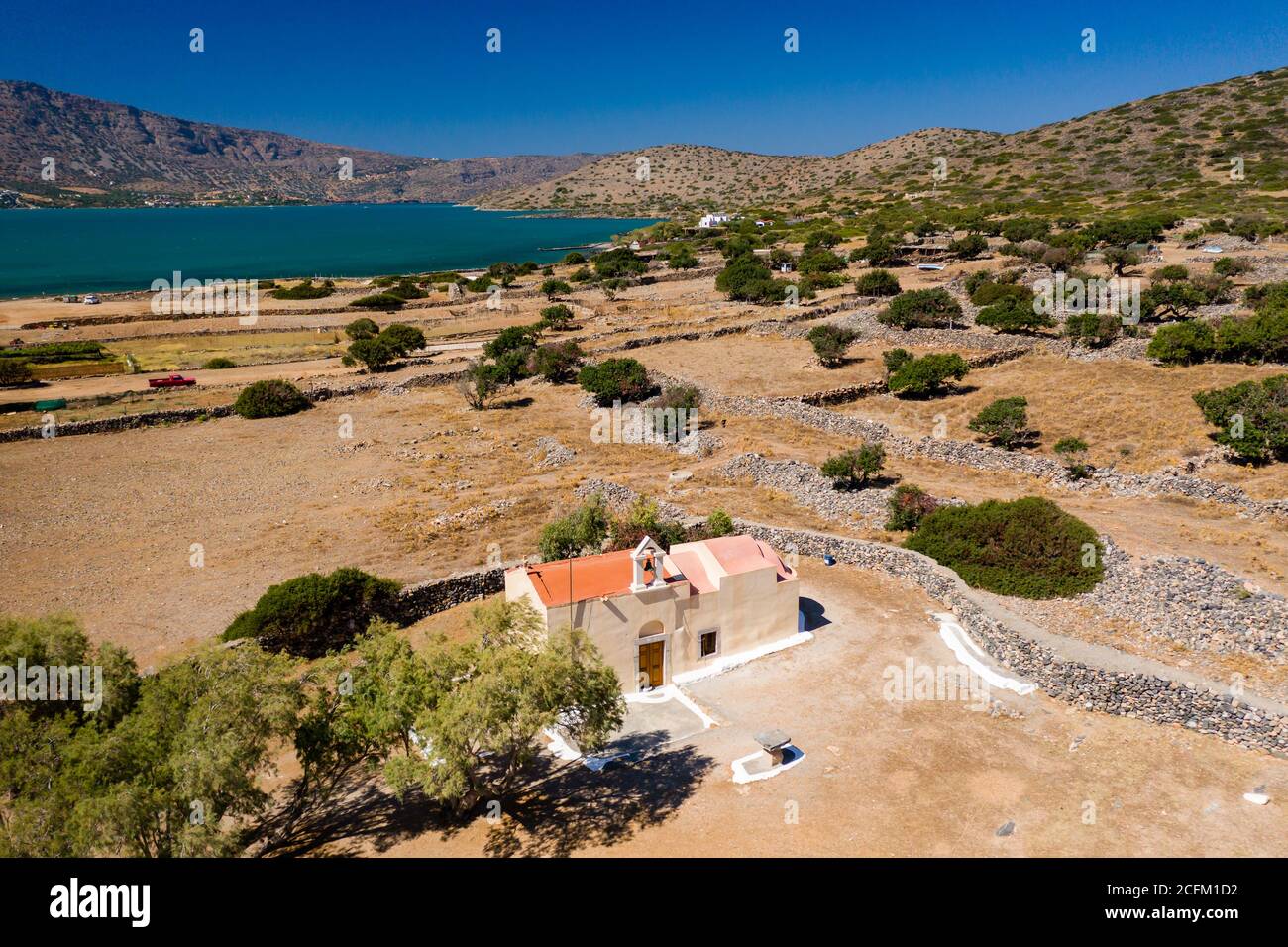 Aerial view of a small church next to a blue ocean on a hot Greek ...