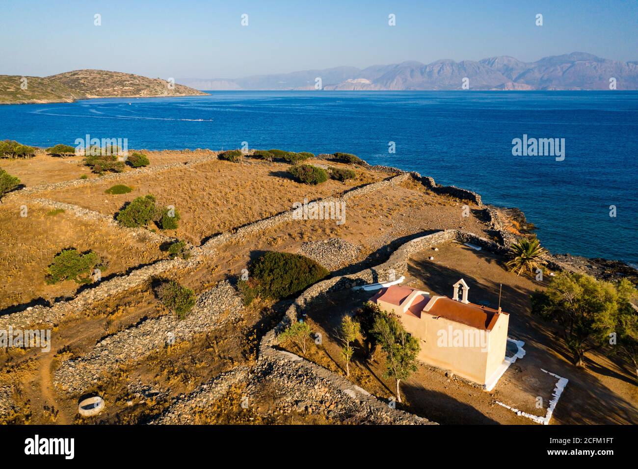 Aerial view of a small church next to a blue ocean on a hot Greek ...