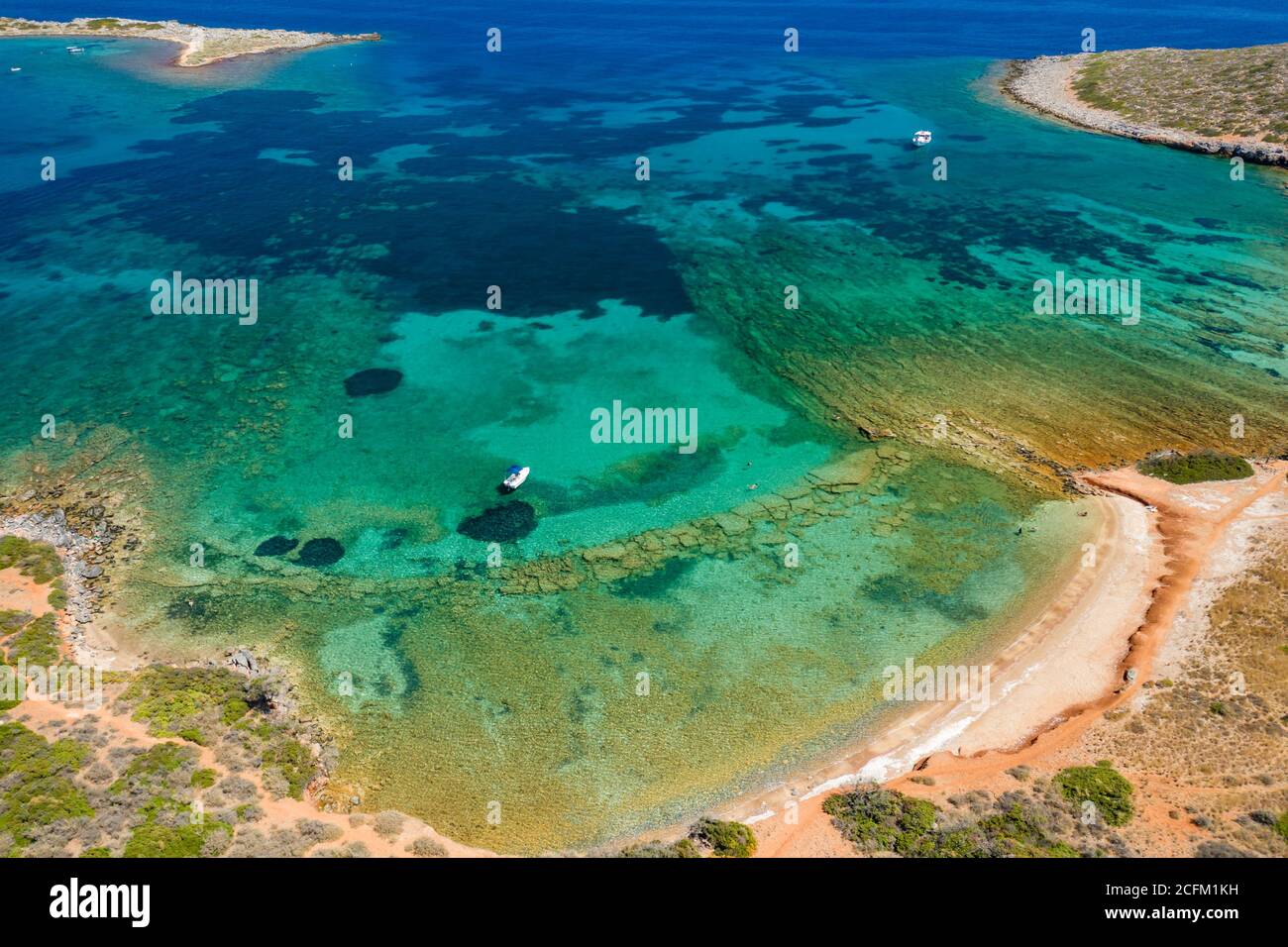 Aerial view of a small island and boats in a crystal clear blue ocean ...