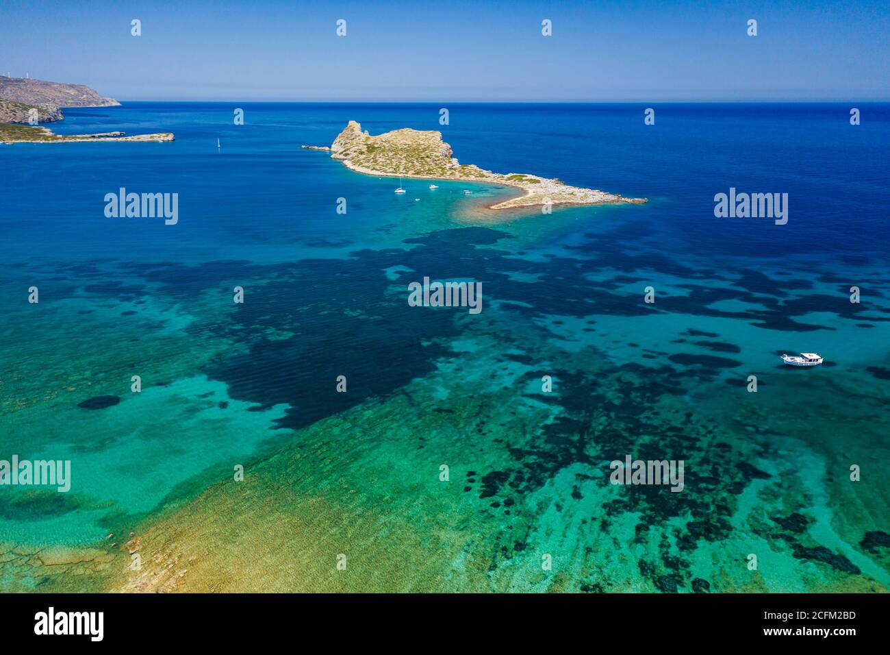 Aerial view of boats in a crystal clear blue ocean next to a small ...