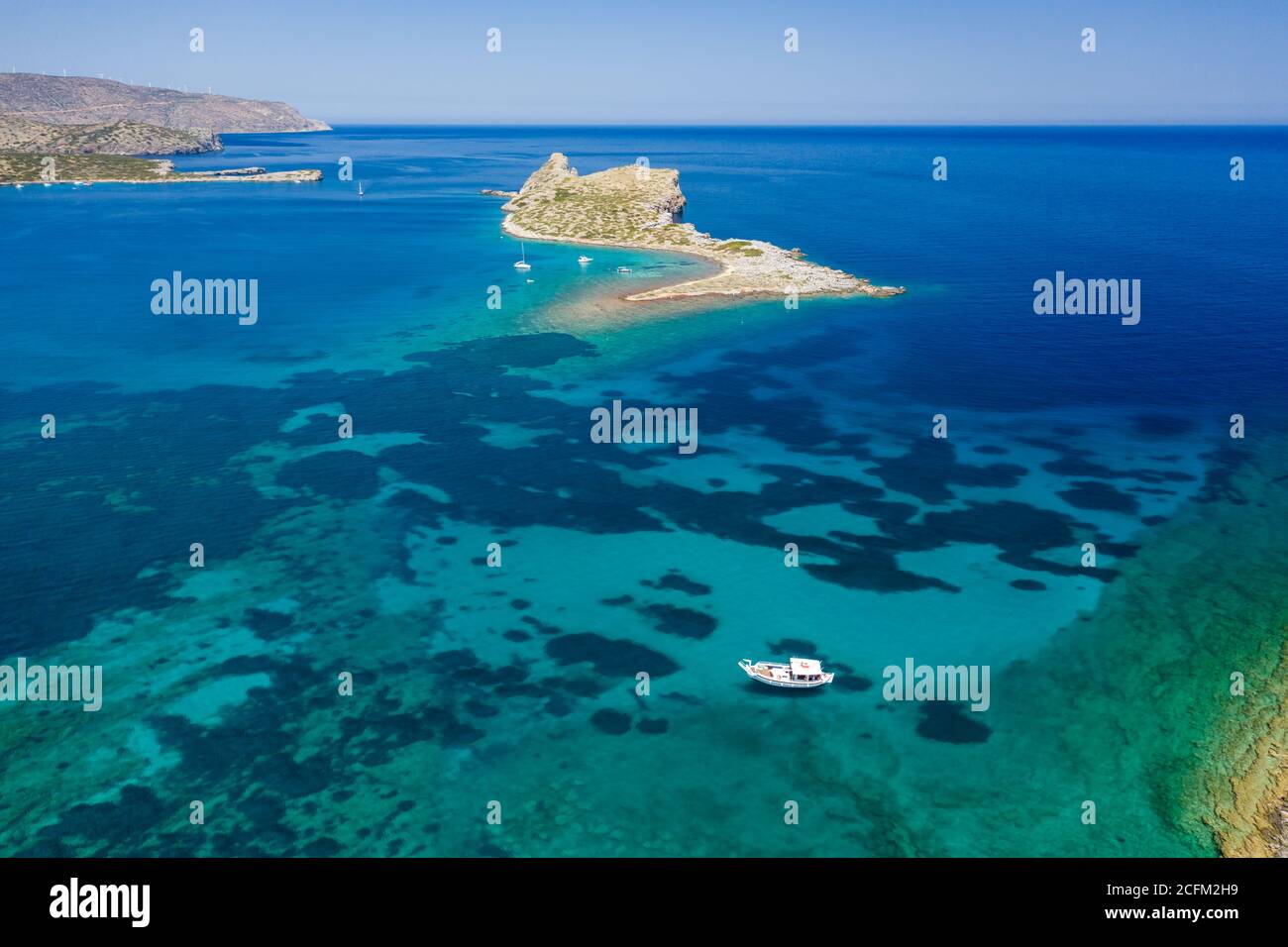 Aerial view of a small island and boats in a crystal clear blue ocean ...