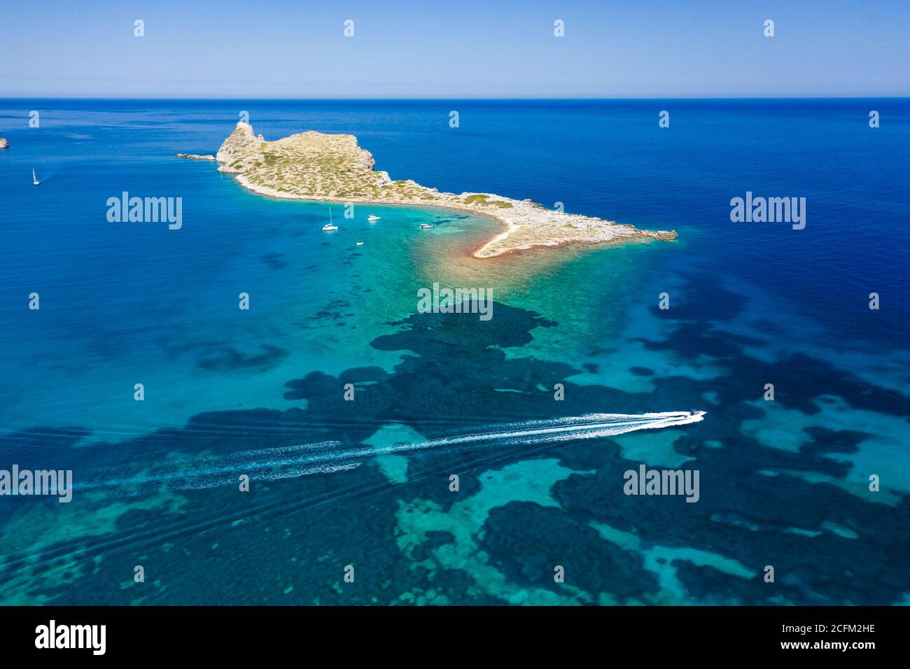 Aerial view of boats in a crystal clear blue ocean next to a small ...