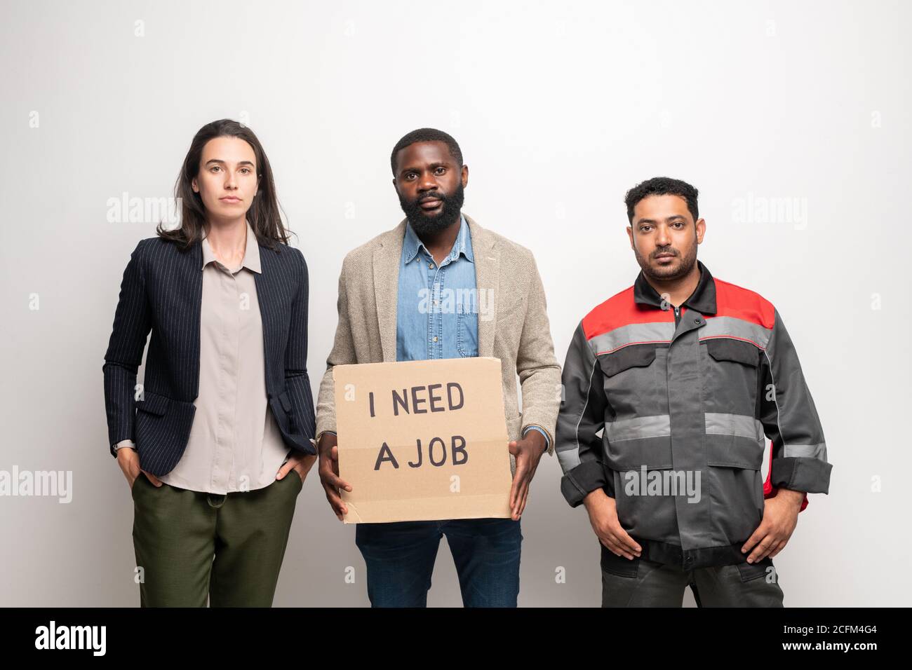 Three young intercultural jobless people standing by wall in front of ...