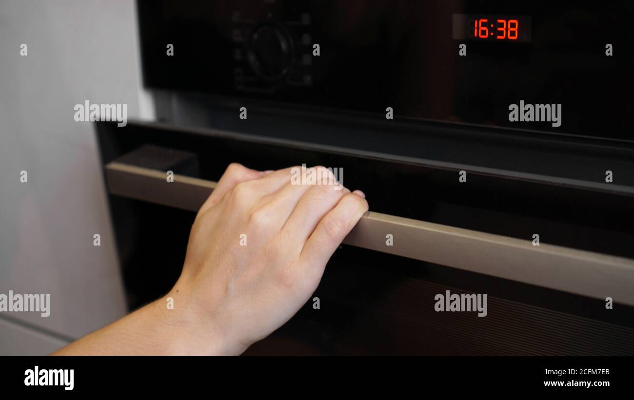 Close up of women hand opening the oven door to control the roast ...