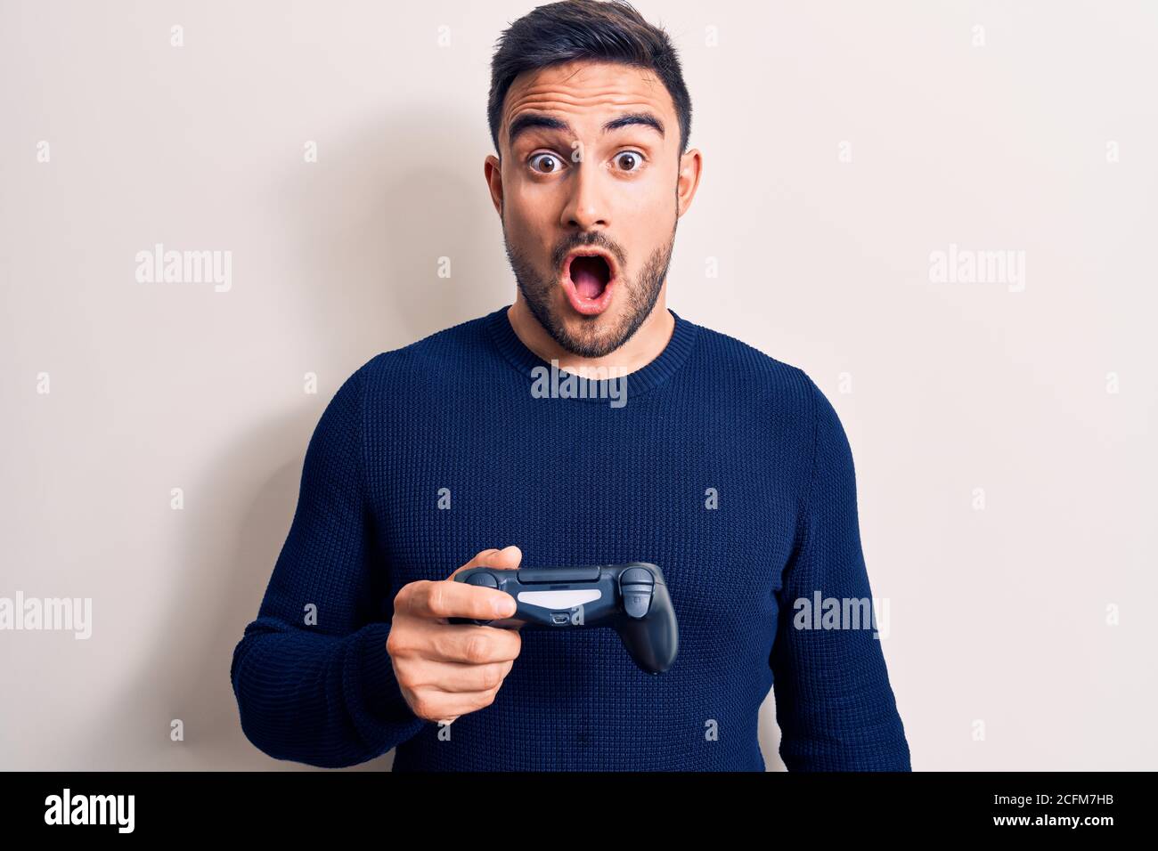 Handsome gamer man with beard playing video game using gamepad over ...