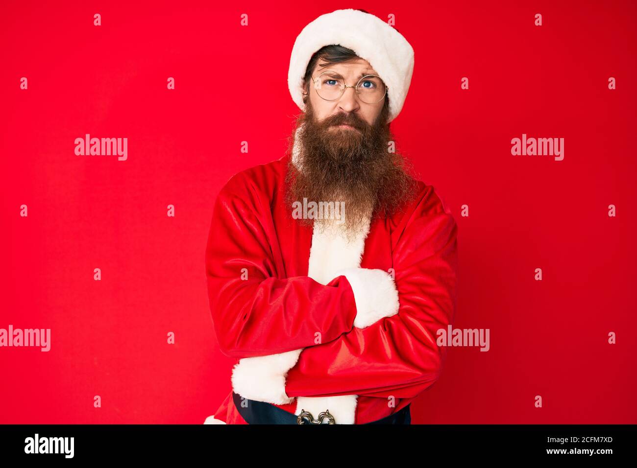 Handsome young red head man with long beard wearing santa claus costume ...