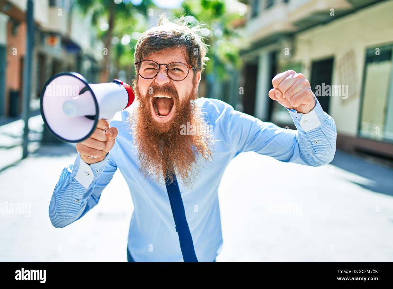 Young redhead businessman with angry expression. Screaming using ...
