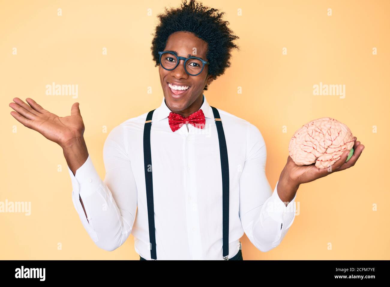 Handsome african american nerd man with afro hair holding brain ...