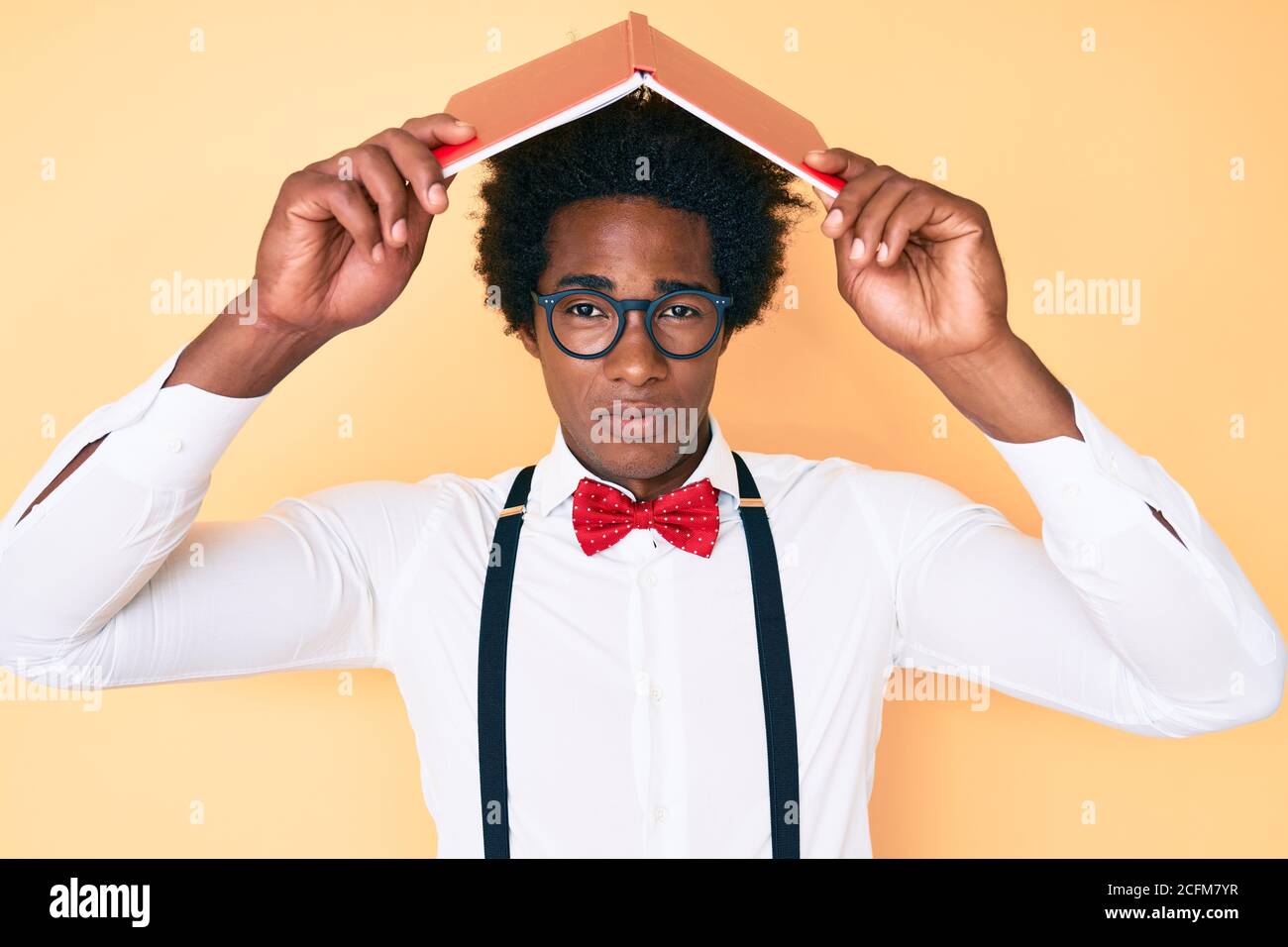 Handsome african american nerd man with afro hair holding book over ...