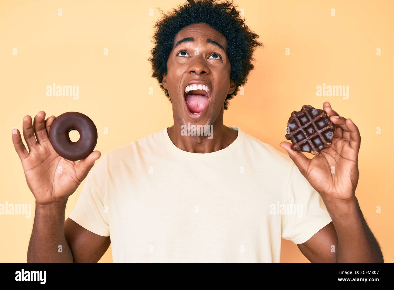 Handsome african american man with afro hair holding chocolate donut ...