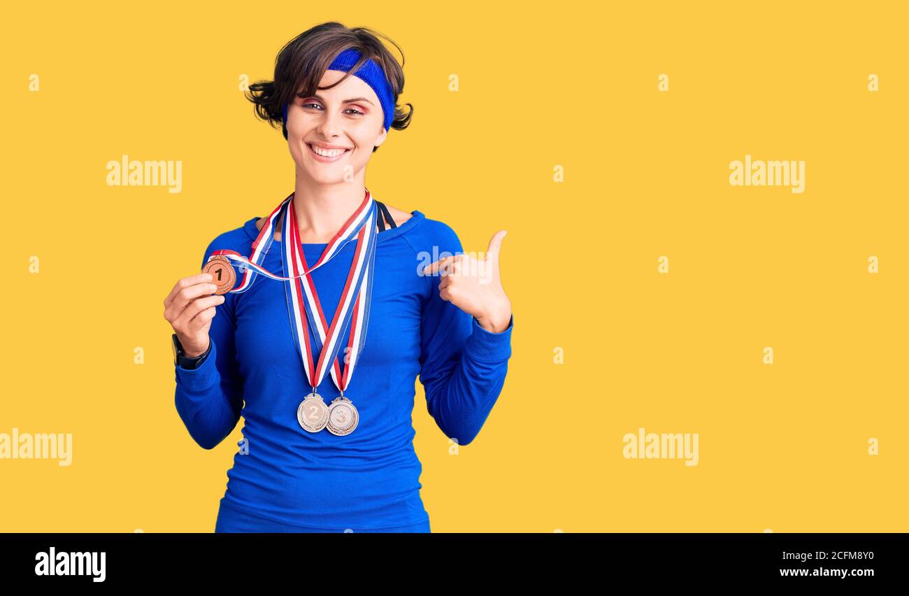 Beautiful young woman with short hair wearing winner medals pointing ...