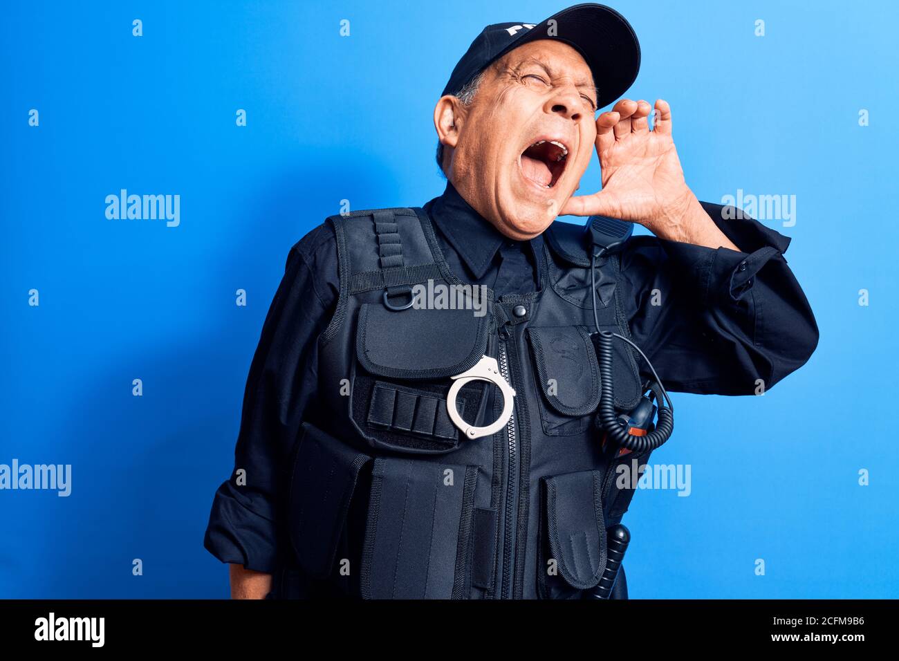Senior man with grey hair wearing police uniform shouting and screaming ...