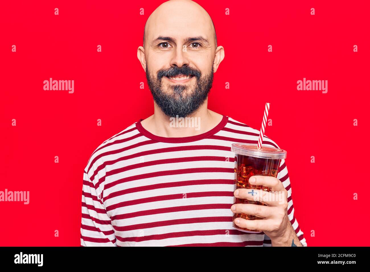 Young handsome man drinking glass of cola beverage looking positive and ...
