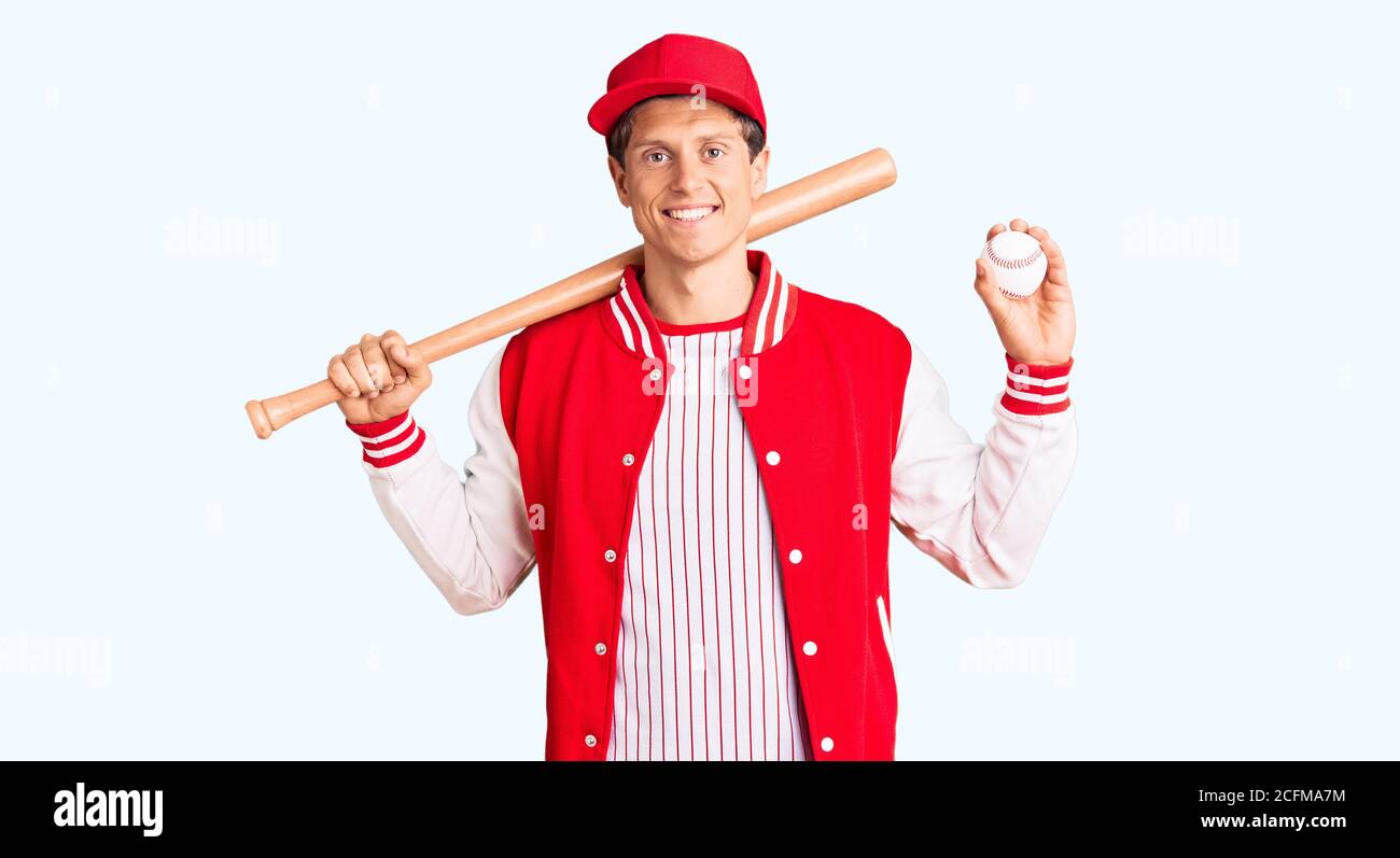 Young handsome man playing baseball holding bat and ball looking ...