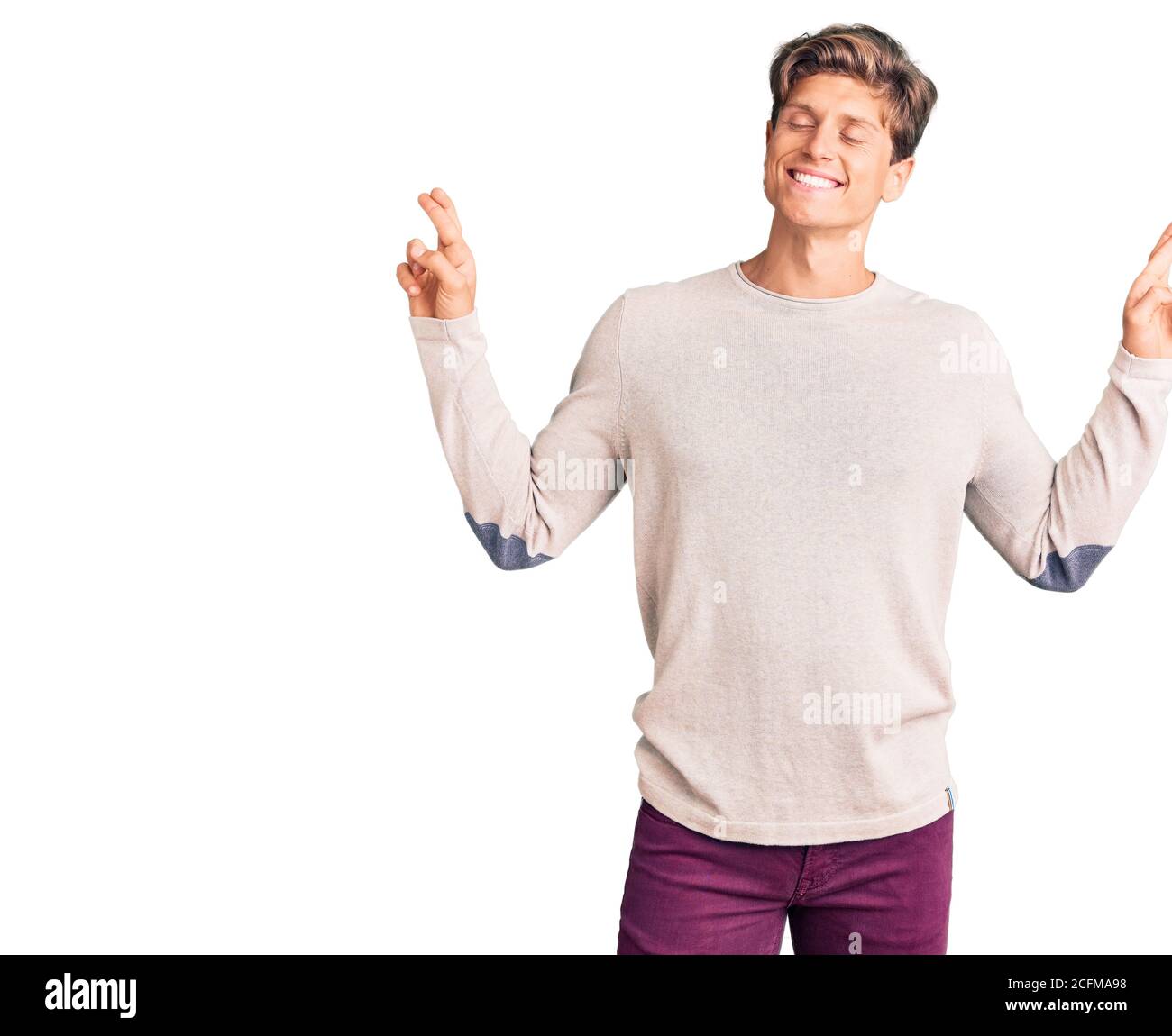 Hopeful young man crossing fingers Cut Out Stock Images & Pictures - Alamy