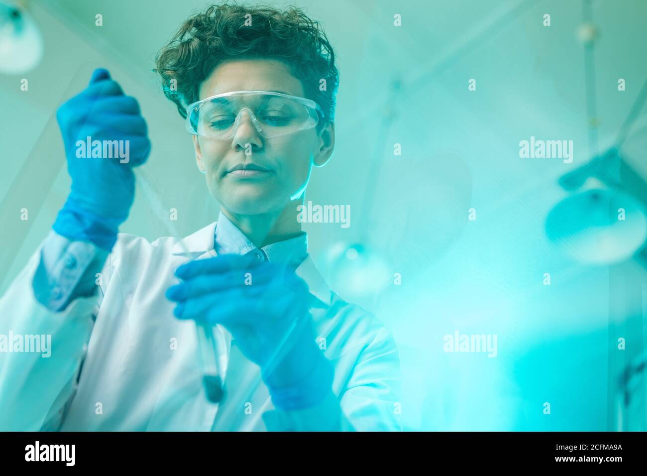 Young female scientist or researcher dropping chemical substance into ...