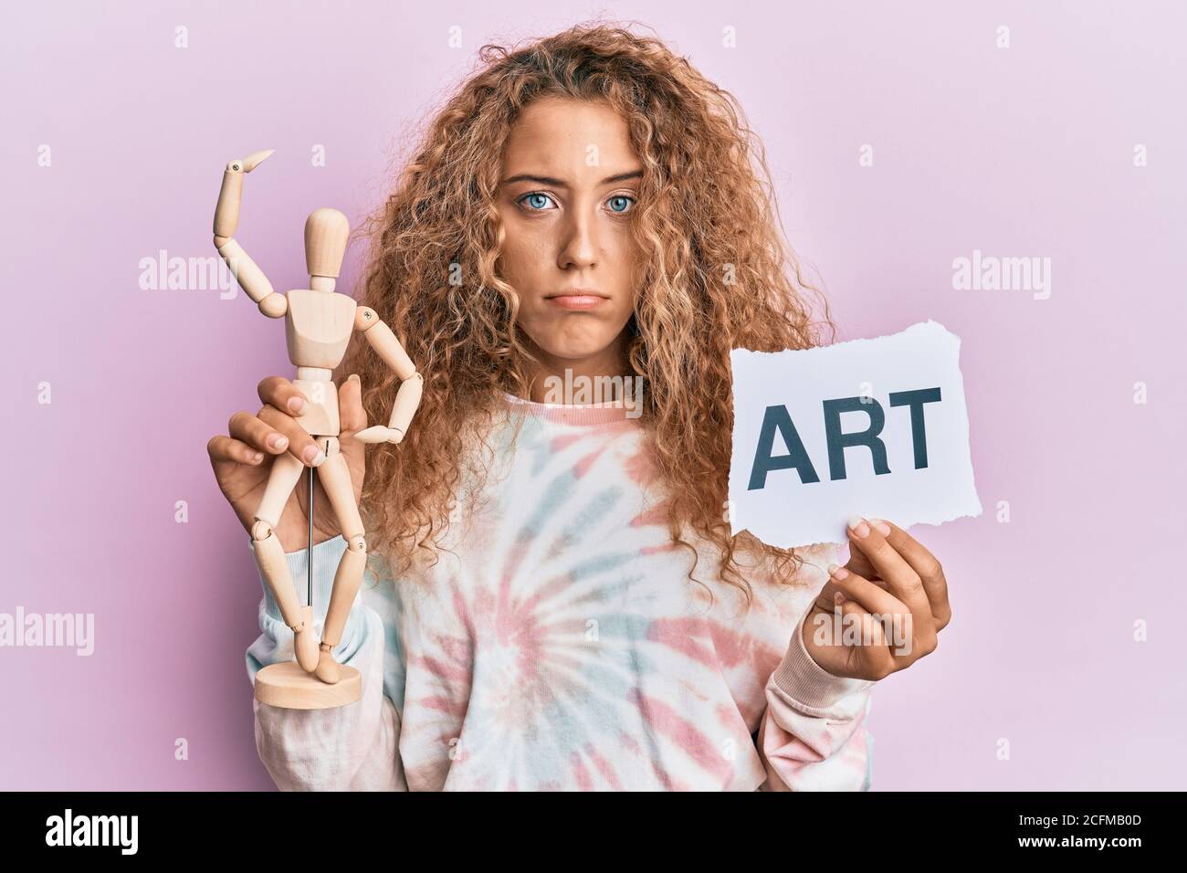 Beautiful caucasian teenager girl holding wooden manikin and art word ...