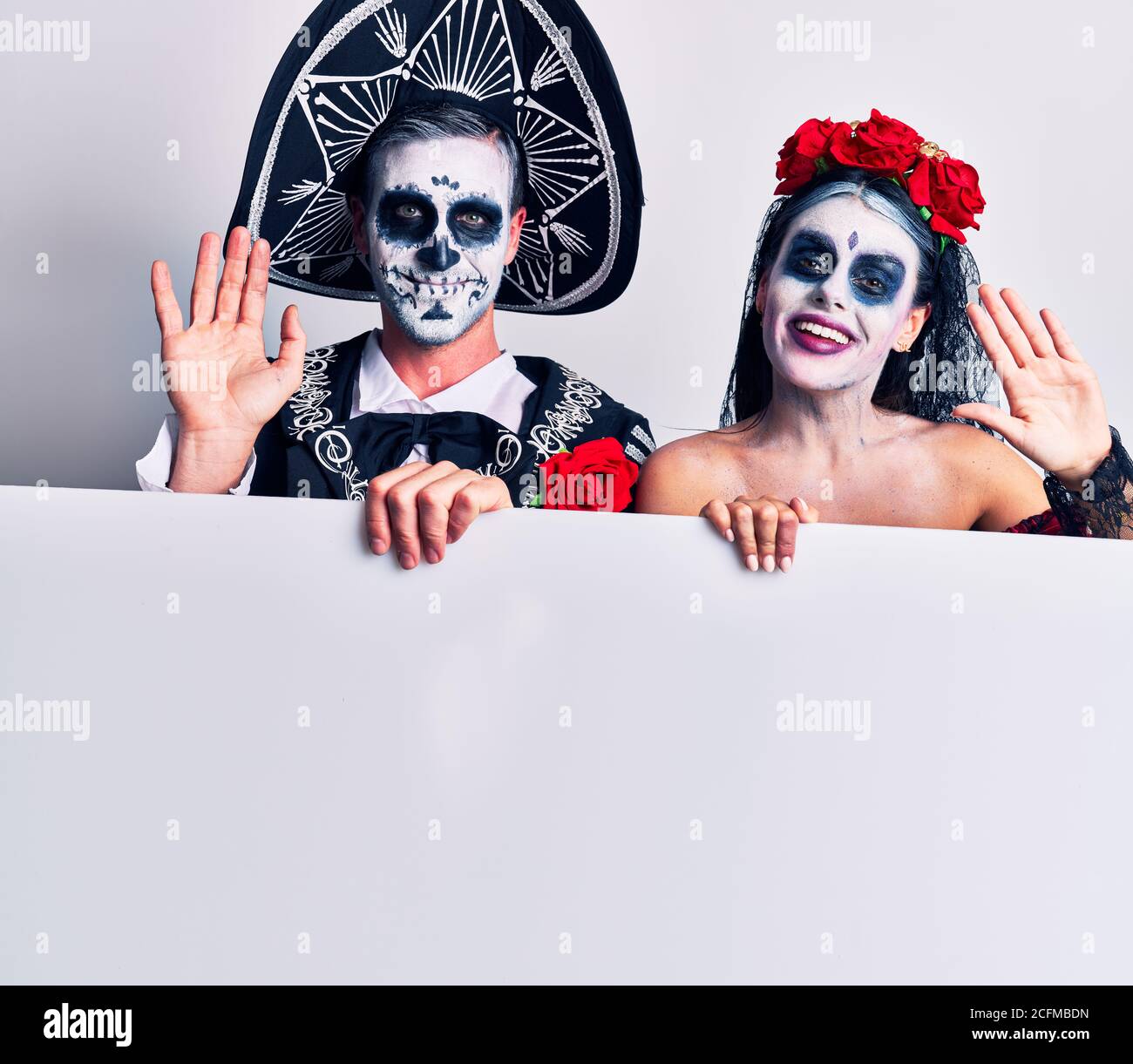 Young couple wearing mexican day of the dead costume holding blank ...