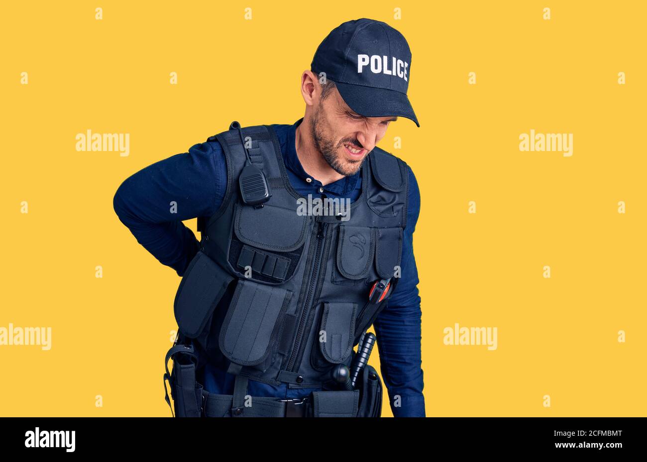 Young handsome man wearing police uniform suffering of backache ...