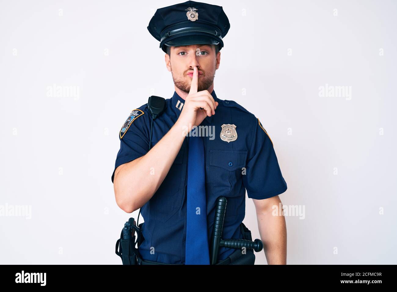 Young caucasian man wearing police uniform asking to be quiet with ...