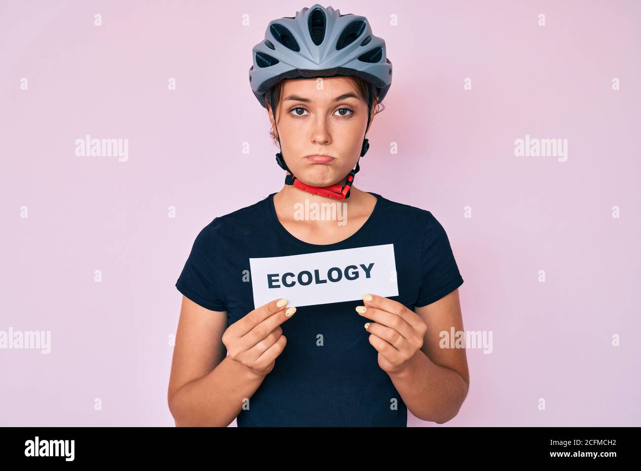Beautiful caucasian woman wearing bike helmet holding ecology word ...
