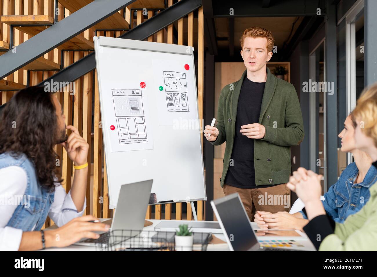 Young serious coach explaining characteristics of new mobile ...