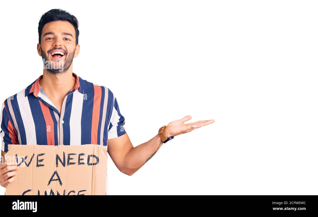 Young handsome hispanic man holding we need a change banner celebrating ...