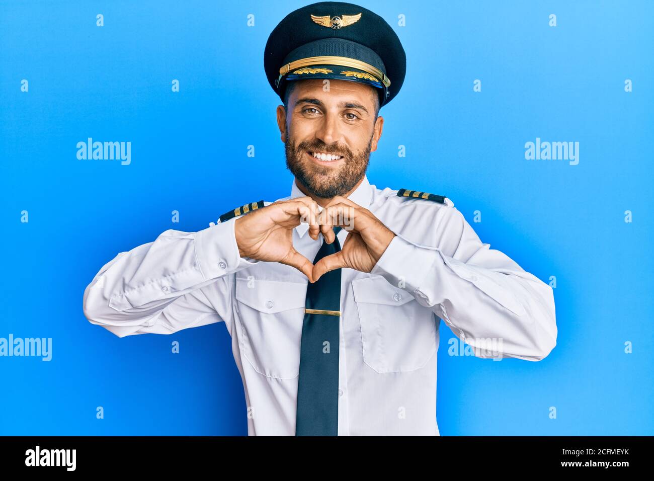 Handsome man with beard wearing airplane pilot uniform smiling in love ...