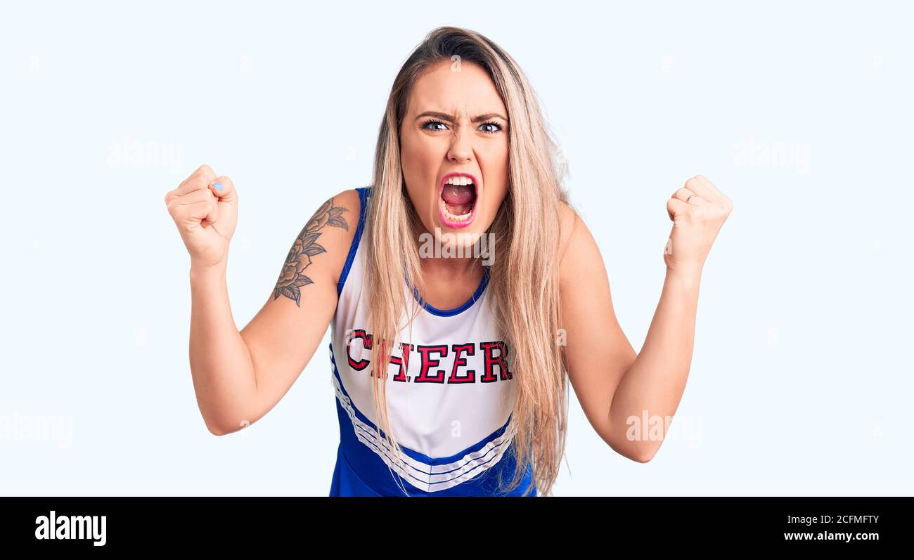 Young beautiful blonde woman wearing cheerleader uniform angry and mad ...