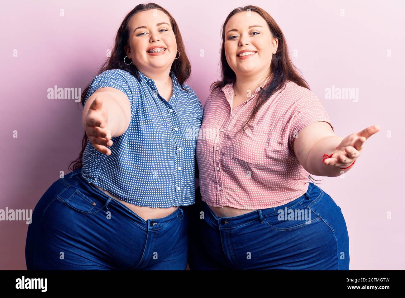 Young plus size twins wearing casual clothes looking at the camera ...